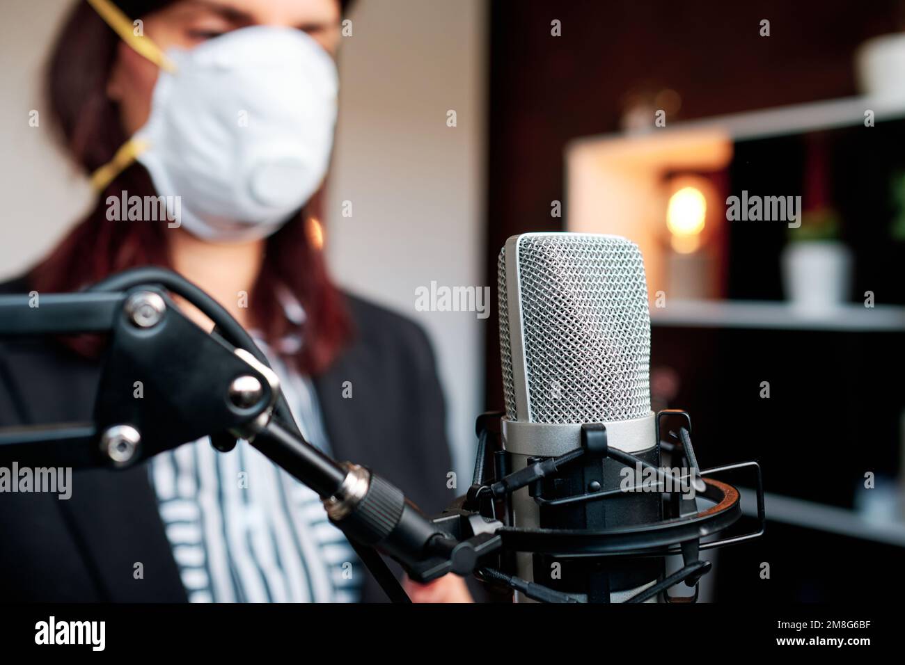 Woman with face mask broadcasting her podcast with a microphone from ...
