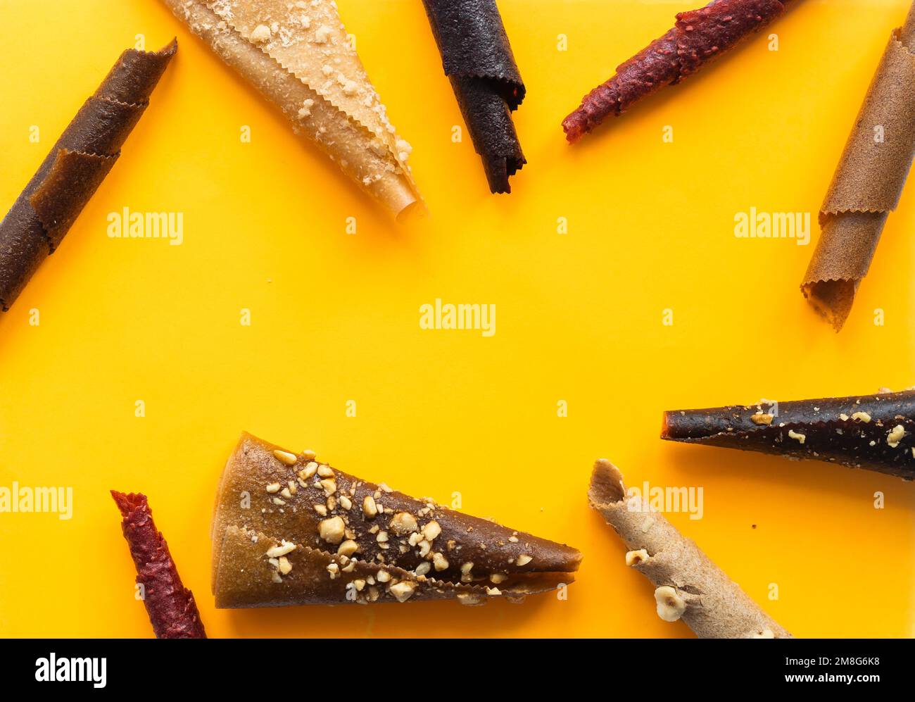 fruit rolls of orange, mango, banana on a yellow background close-up ...