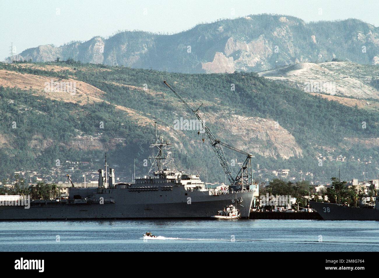 A large harbor tug maneuvers the amphibious transport dock USS DUBUQUE ...