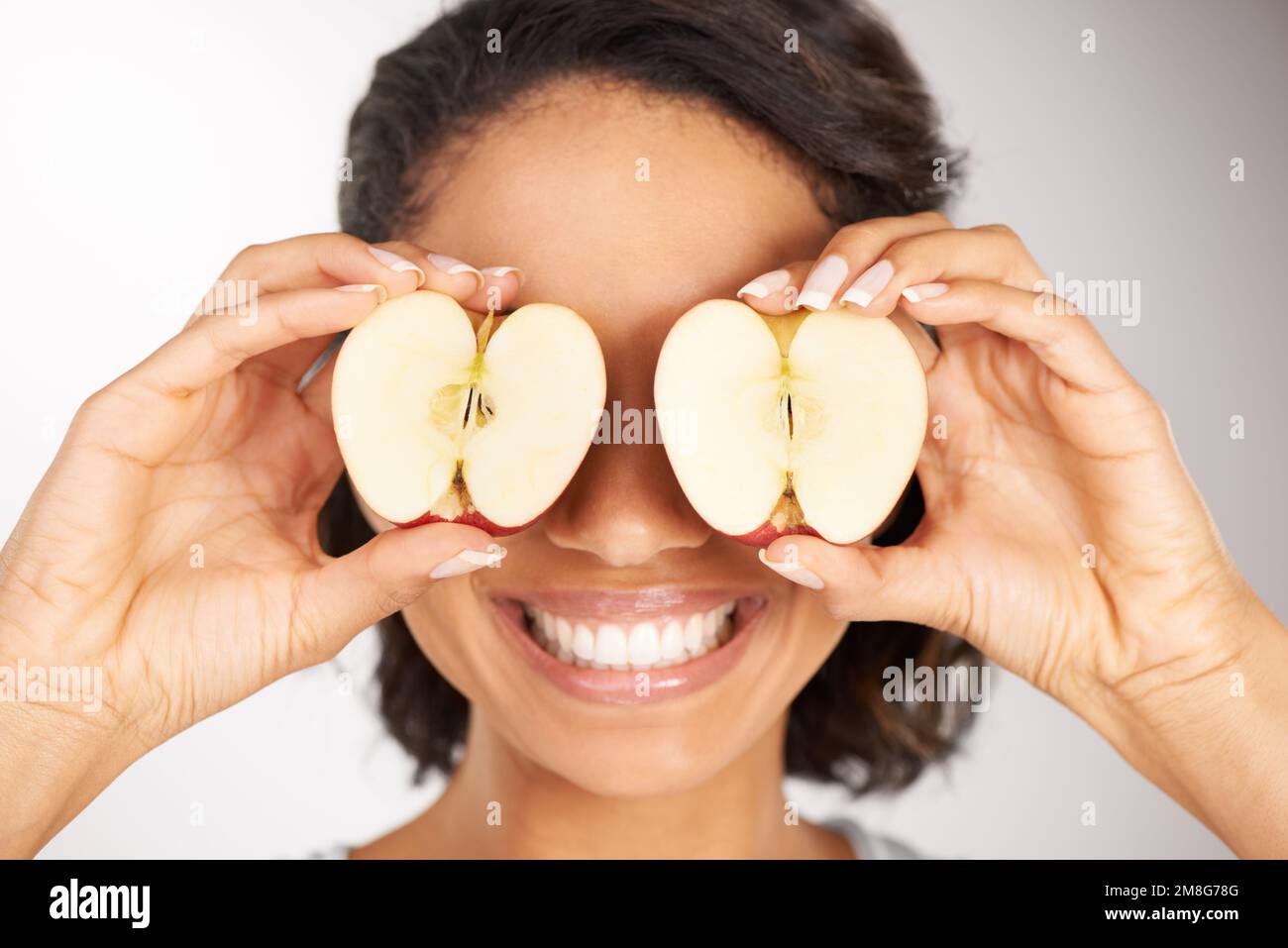 Two halves of a whole. a young woman covering her eyes with two apple ...