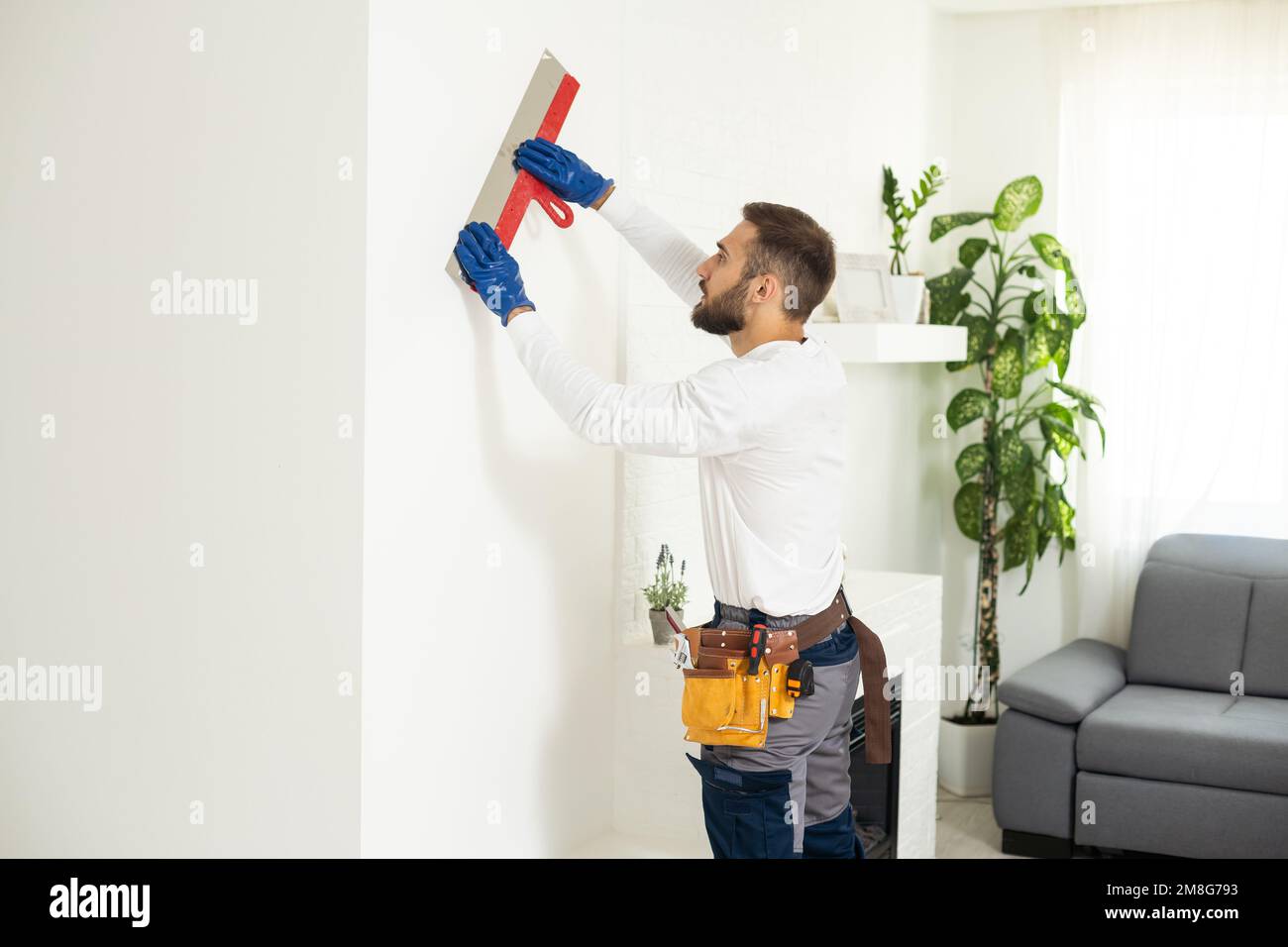 man plasterer construction worker at work, takes plaster from bucket ...