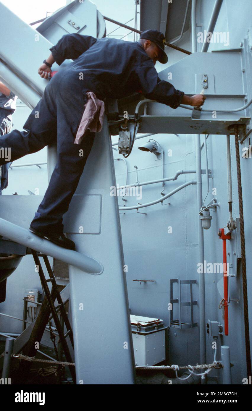 A sailor paints a beam aboard the guided missile destroyer USS ...