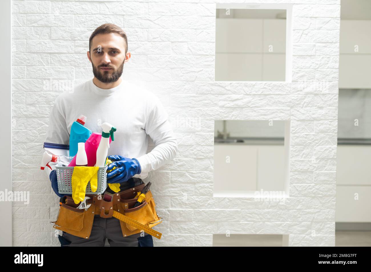 Young male worker of cleaning service with supplies on white background ...