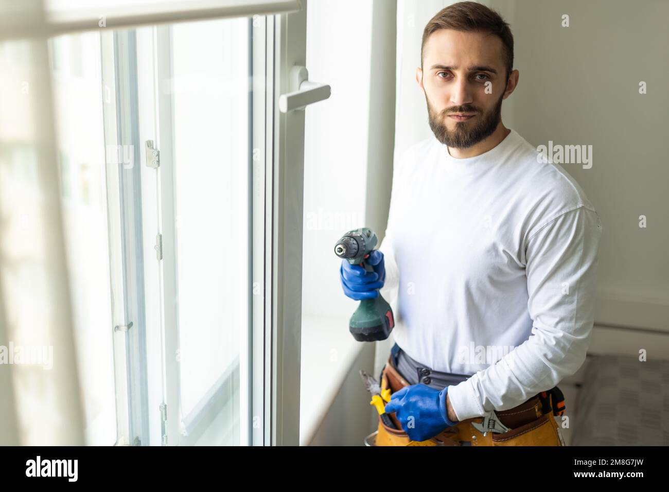 service man installing window with screwdriver Stock Photo - Alamy