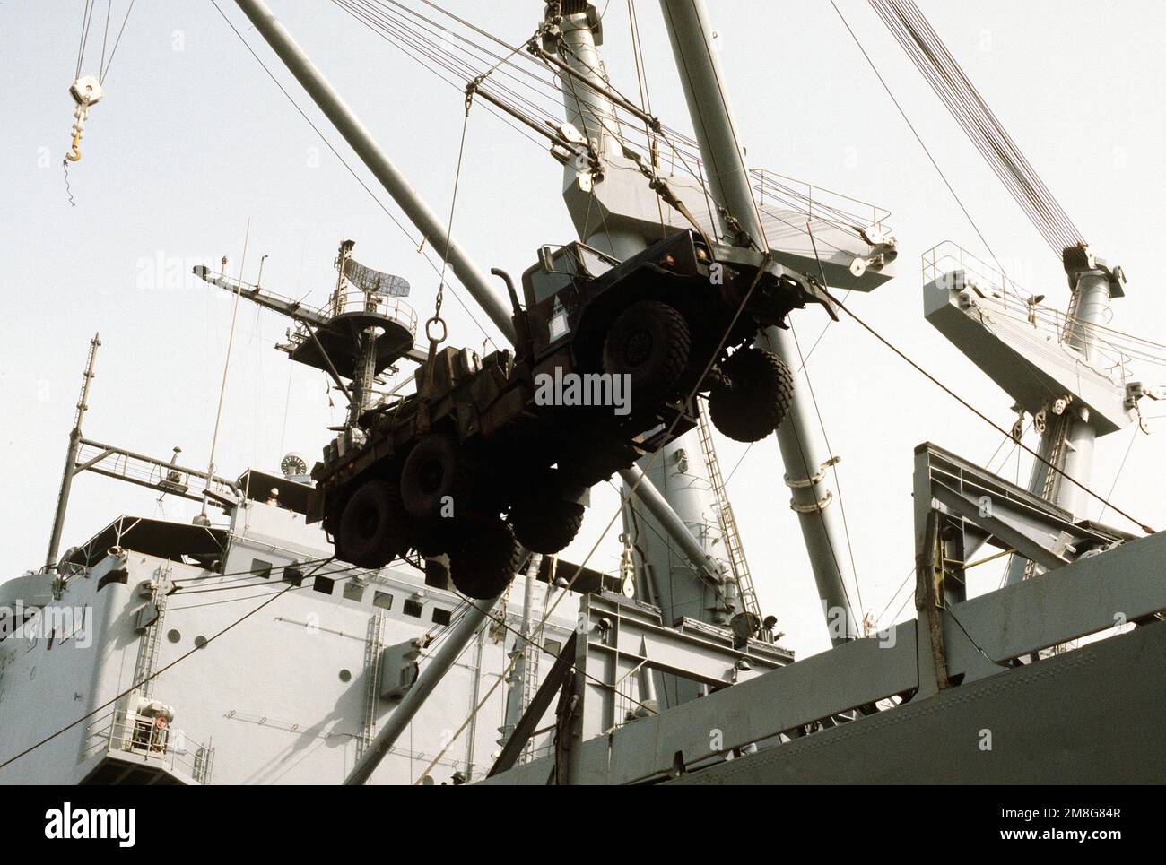 A truck is lowered by crane from the amphibious cargo ship USS DURHAM ...