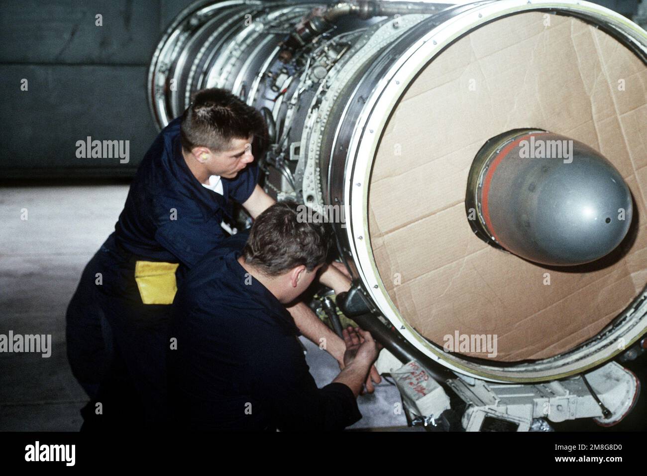 Aviation machinist's mates work on an engine of a Fighter Squadron 124 ...