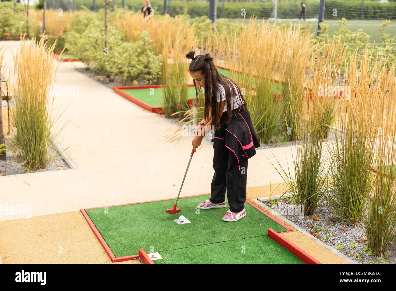 Cute little girl playing mini golf in a park Stock Photo - Alamy
