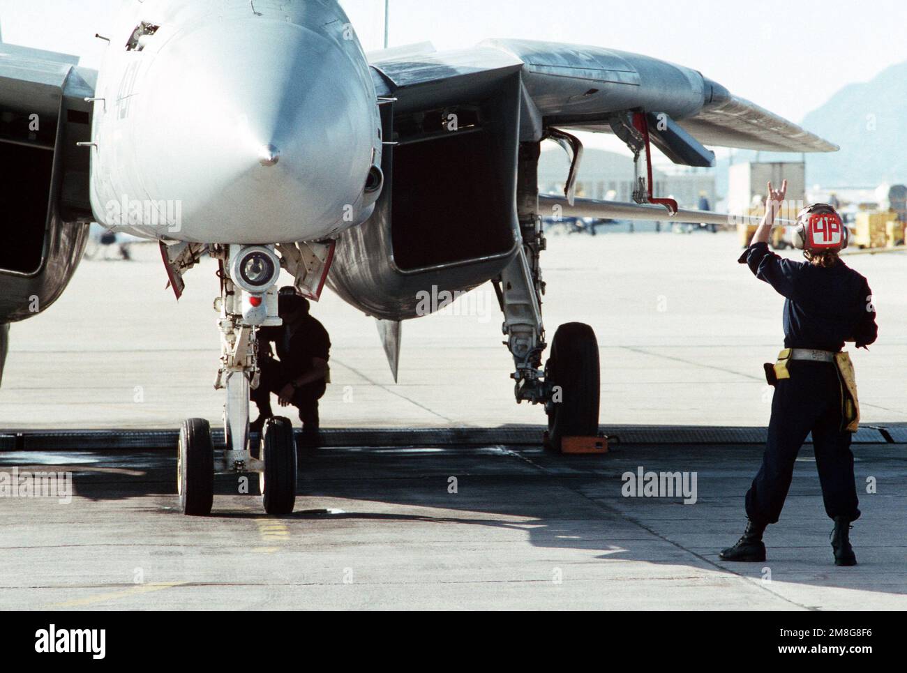A female crewman signals to a fellow crew member during a preflight ...