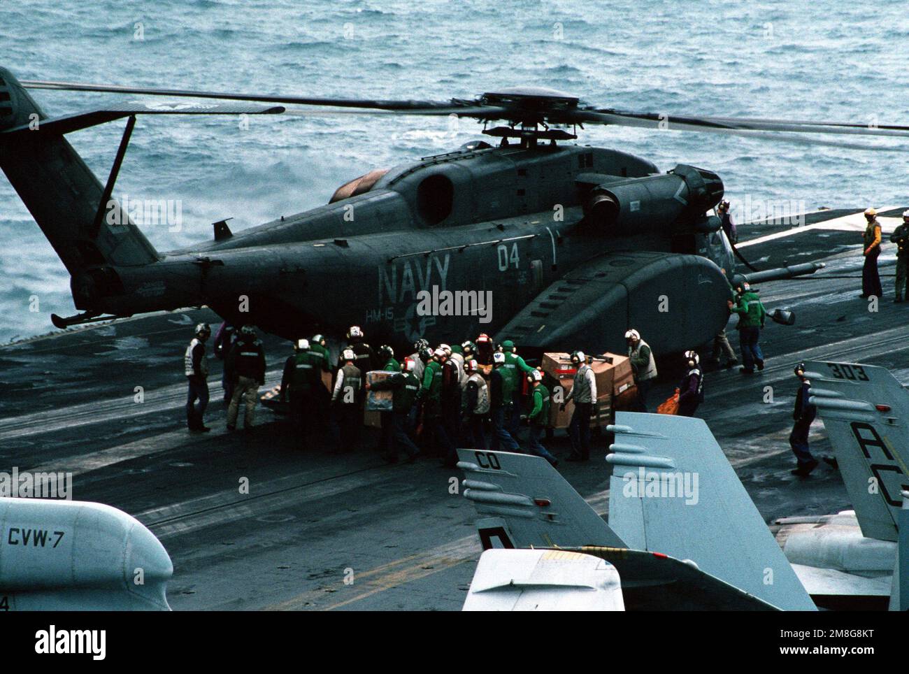 Flight deck crewmen load supplies into an MH-53E Sea Dragon helicopter ...