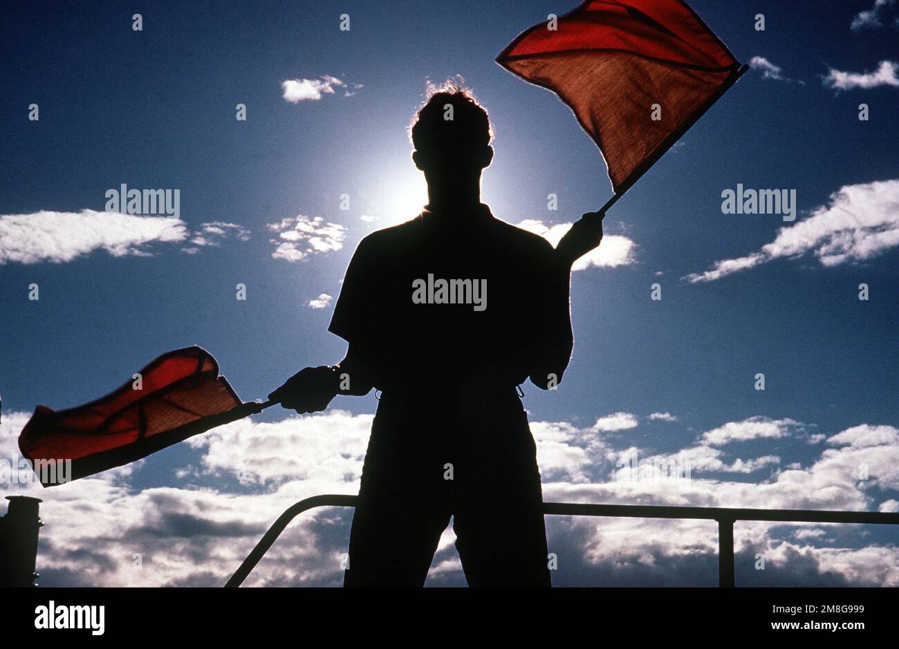 The sun silhouettes a signalman transmitting a message in semaphore on ...