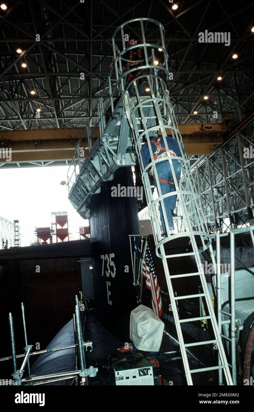 A technician ascends a ladder leading to the top of the sail structure ...