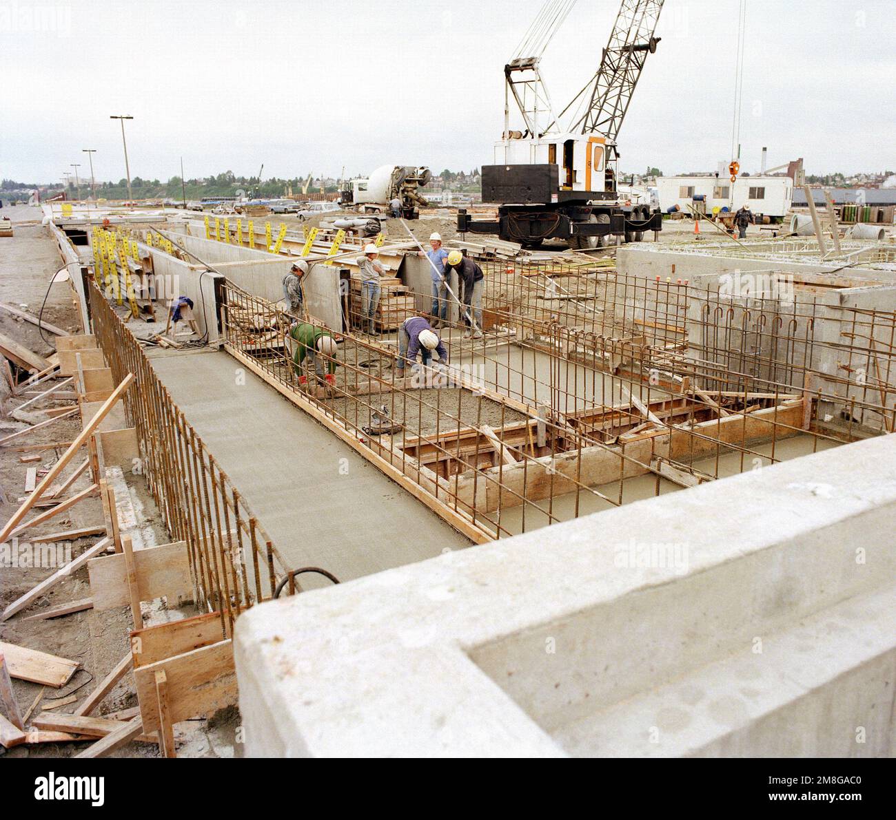 Construction crews smooth concrete during construction of Naval Station ...
