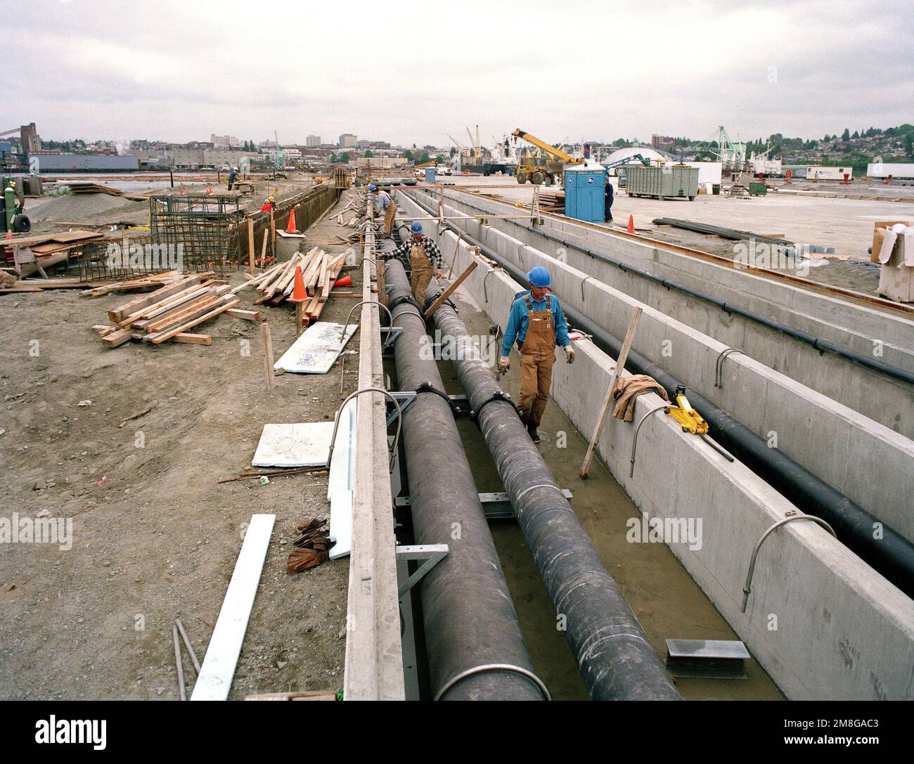 Construction crews check pipe and foundations during construction of ...