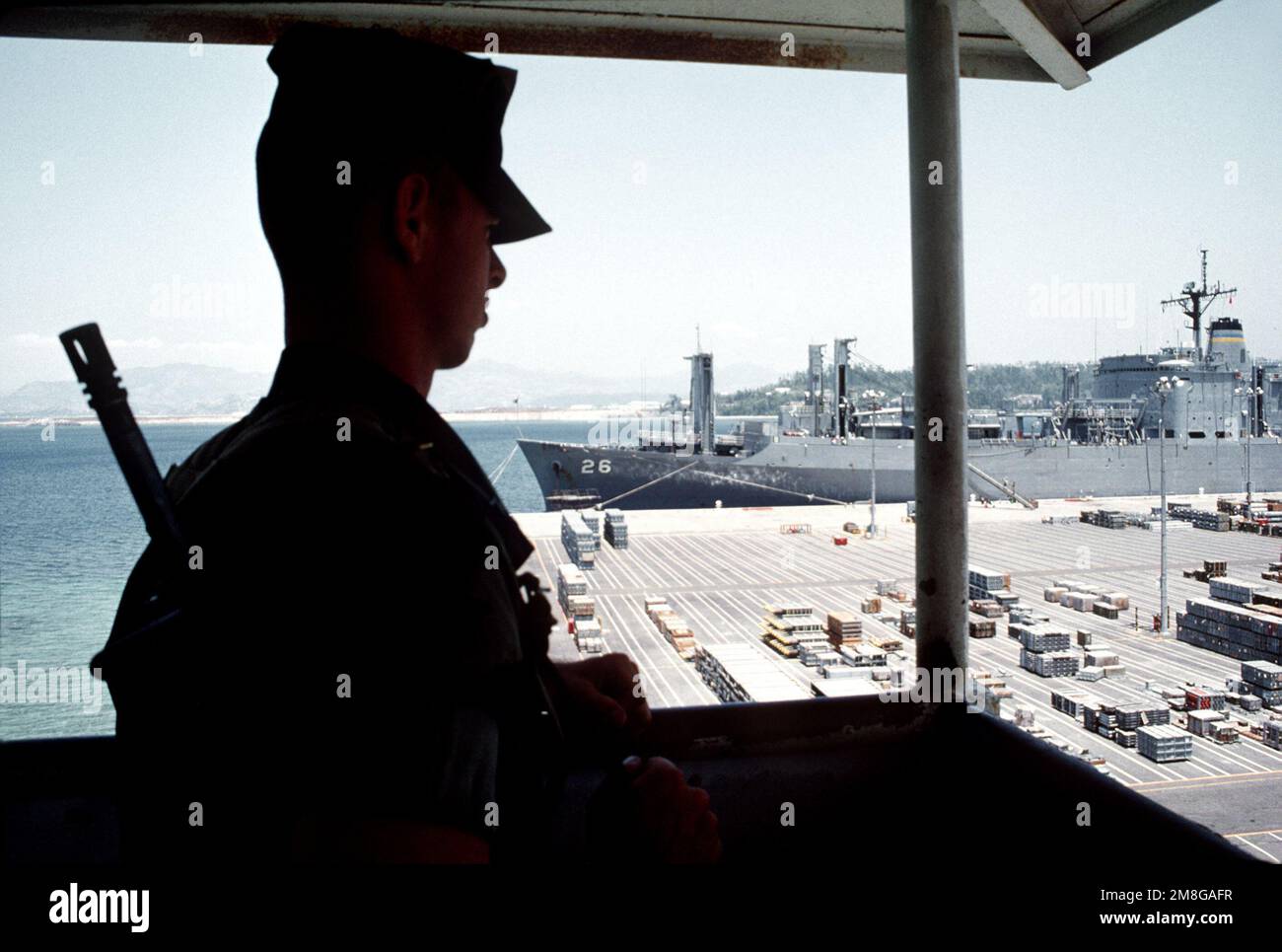 PFC. Darren Borton stands guard over containers of ordnance lining the ...