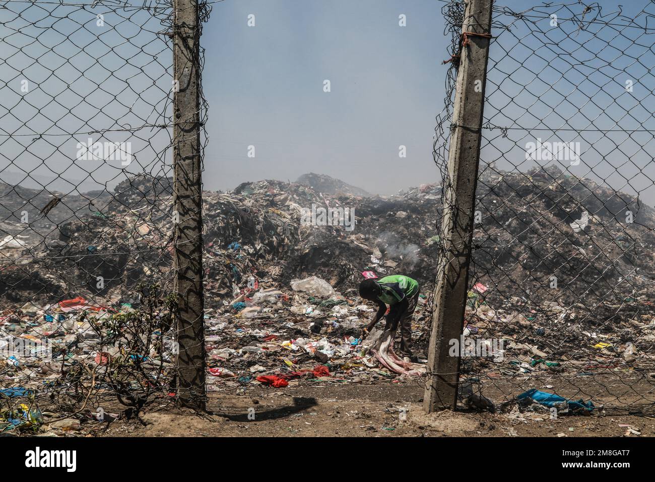A young waste picker recovers waste for recycling amidst heavy smoke ...