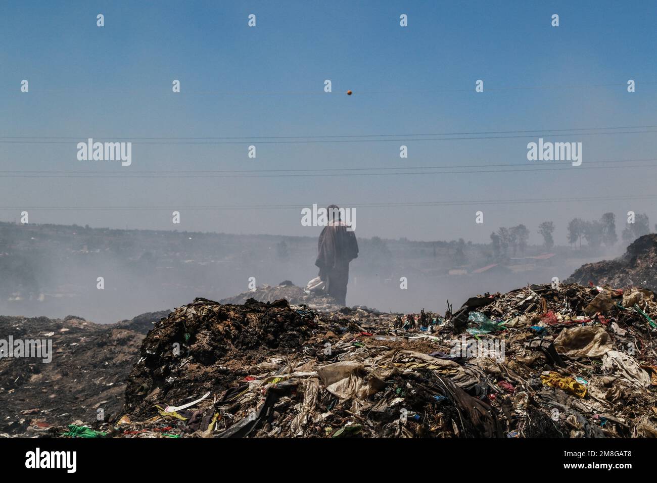 A waste picker recovers waste for recycling amidst heavy smoke from ...
