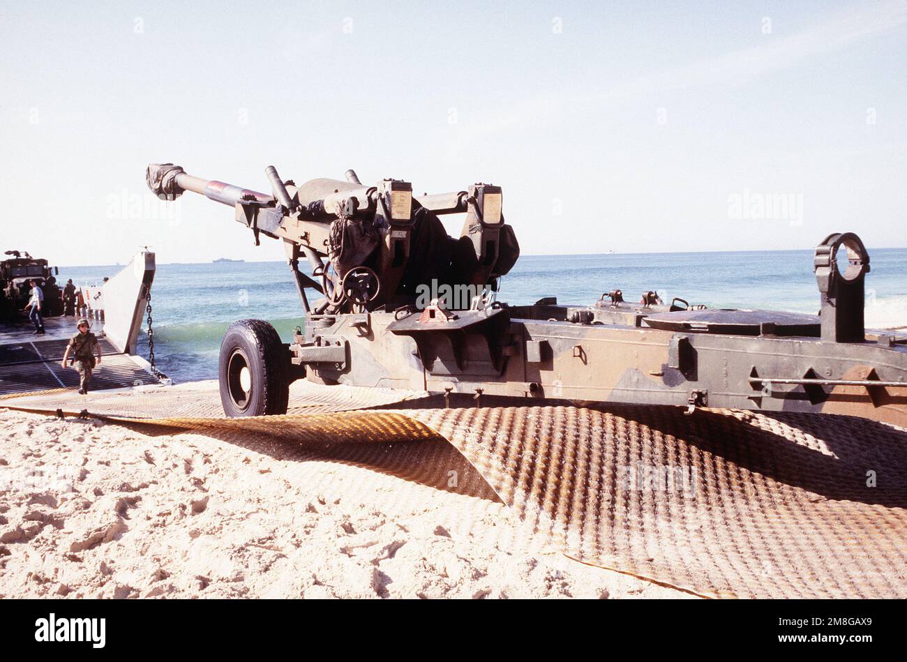 An M-198 155mm howitzer is towed from a utility landing craft from the ...