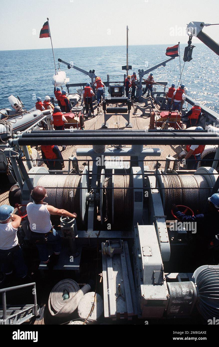 Crew members on an ocean minesweeper stand by at the winch controls as ...