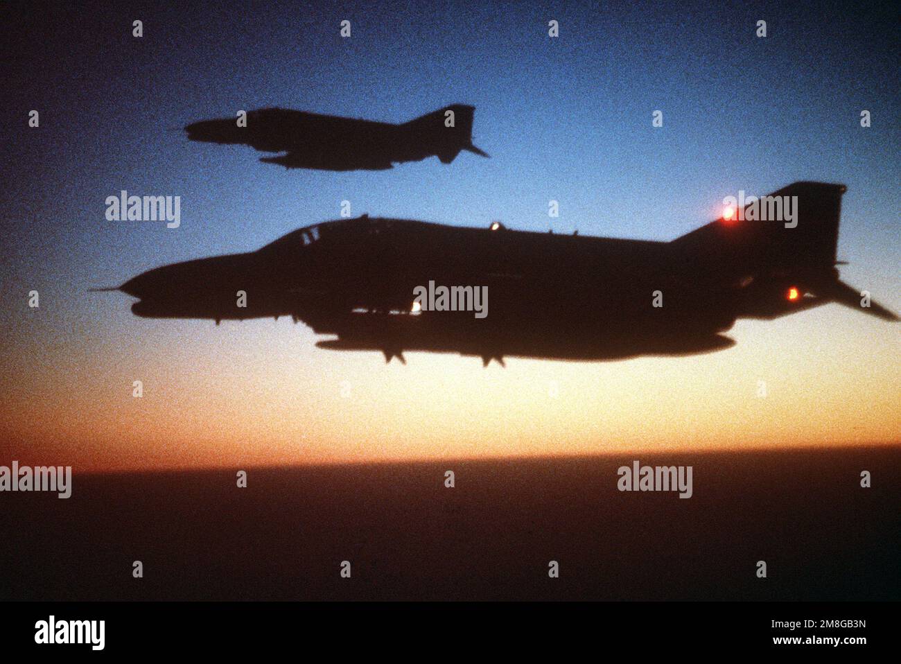 An air-to-air left side view of two F-4G Wild Weasel aircraft at sunset ...