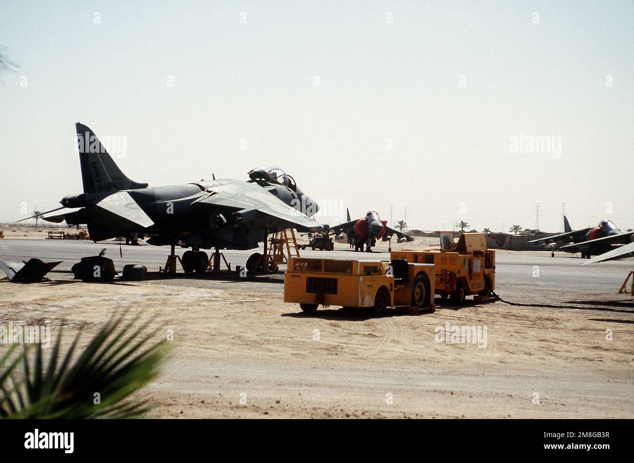 An MD-3A tow tractor and a mobile power plant stand near an AV-8B ...