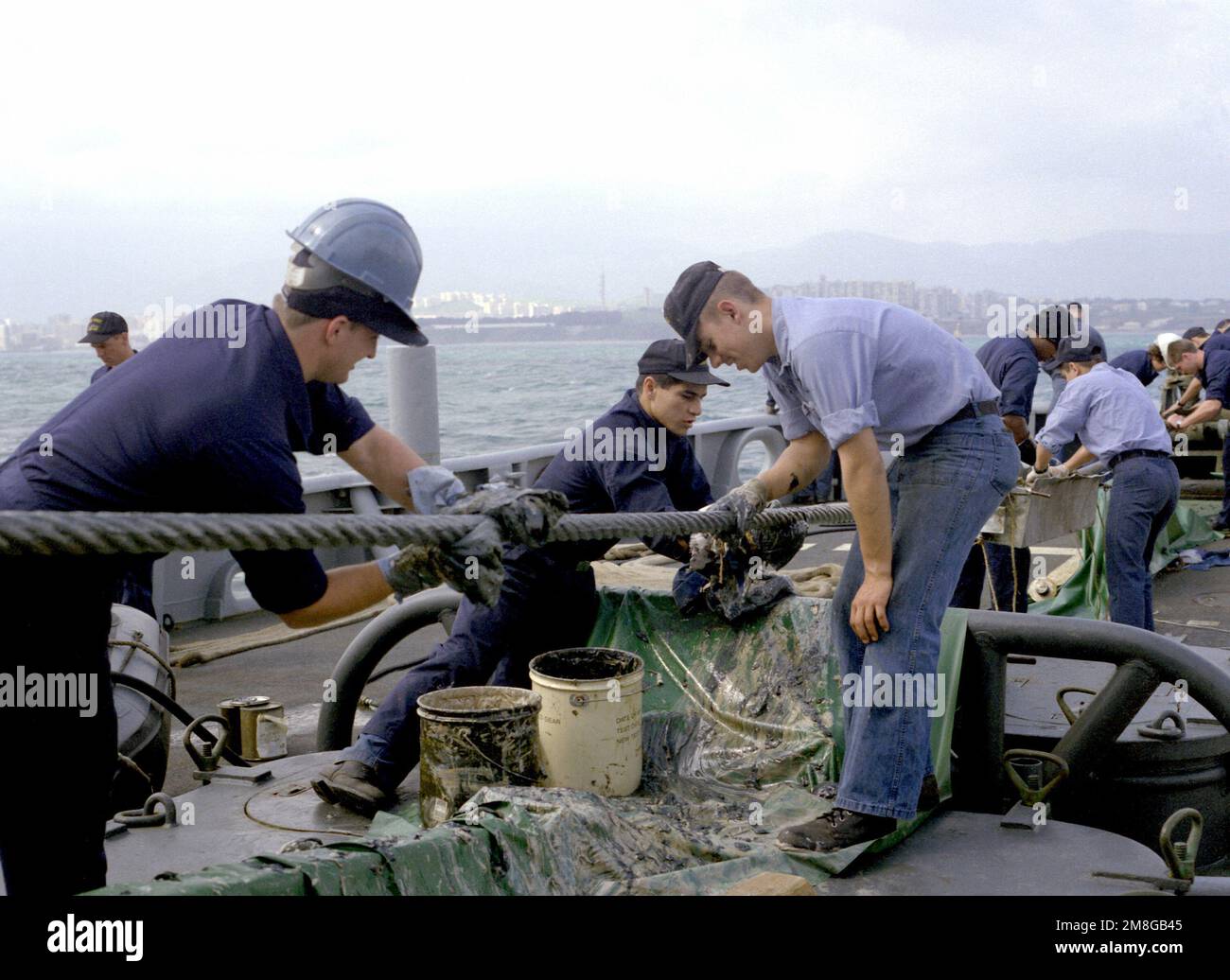Crew members grease the towing line as the salvage ship USS HOIST (ARS ...
