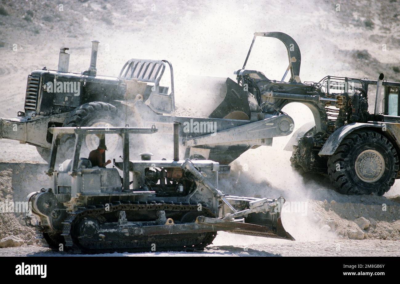 Navy construction battalion personnel use a crawler tractor and wheeled ...