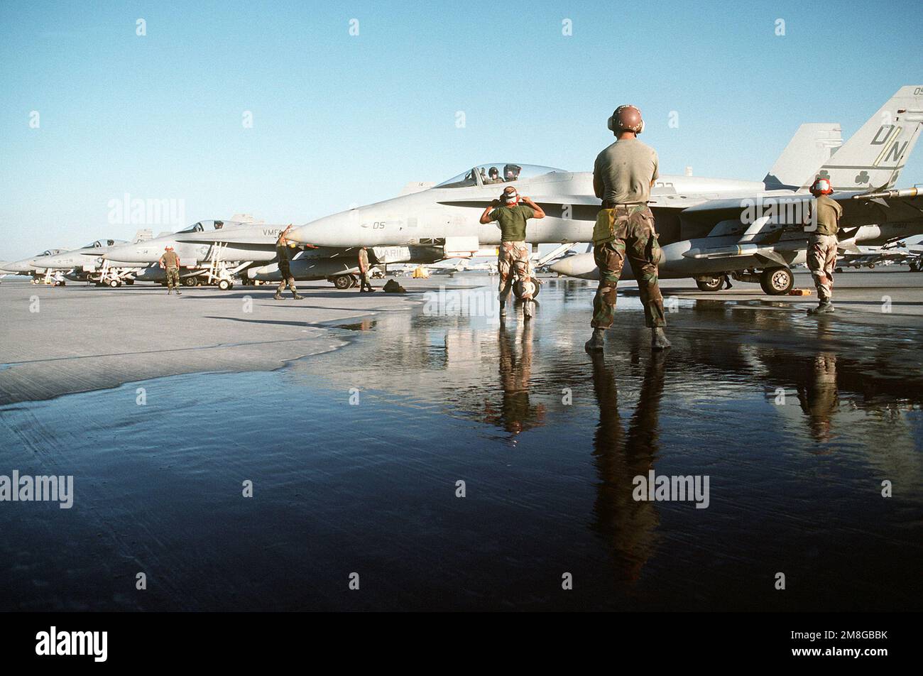 The plane captain marshals an F/A-18 Hornet striker fighter aircraft ...