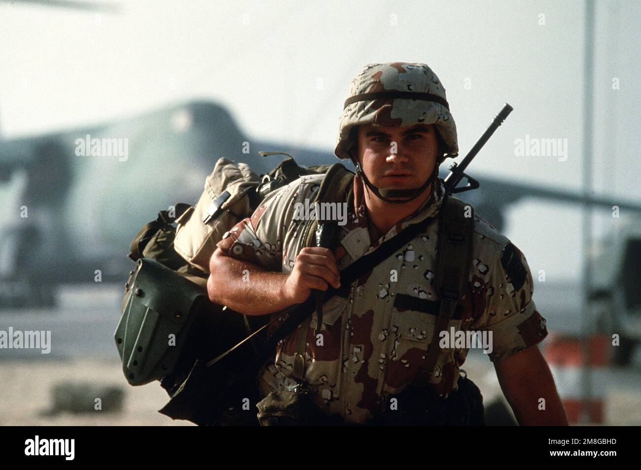 A soldier carries his gear after arriving in Saudi Arabia during ...