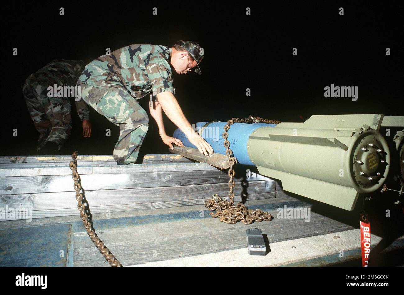 A member of the 2nd Munitions Maintenance Squadron secures a BDU-50 ...
