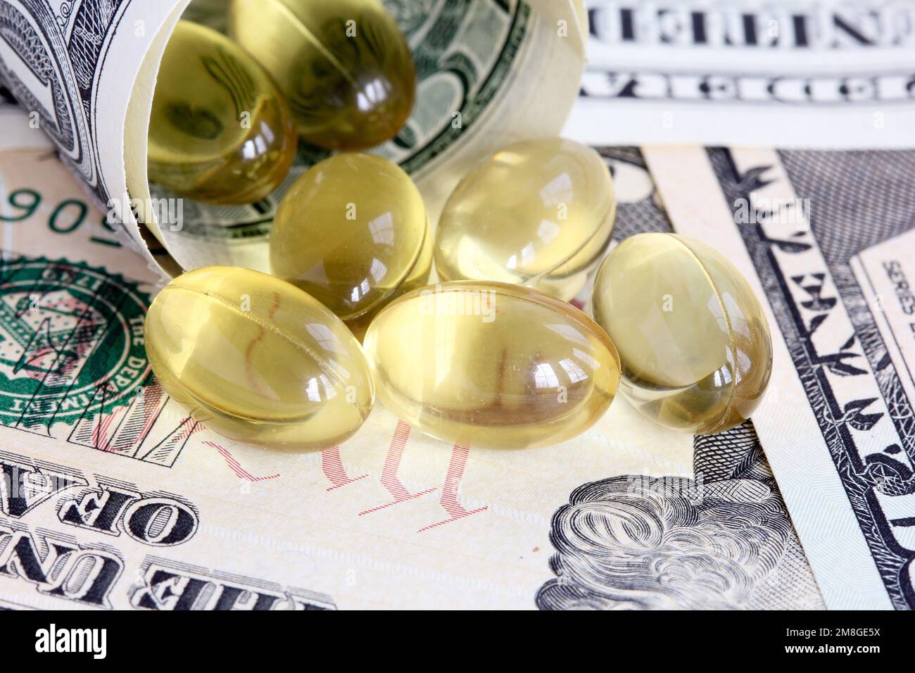 Gel capsules pouring out of rolled dollar bills - symbol of increasing ...