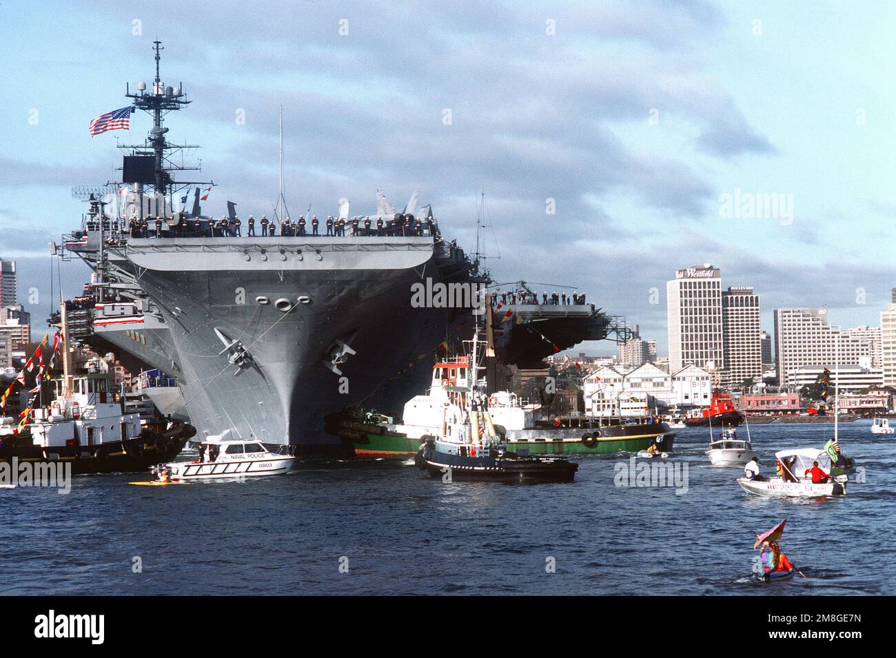 Sailors man the rails as harbor tugs maneuver the aircraft carrier USS ...
