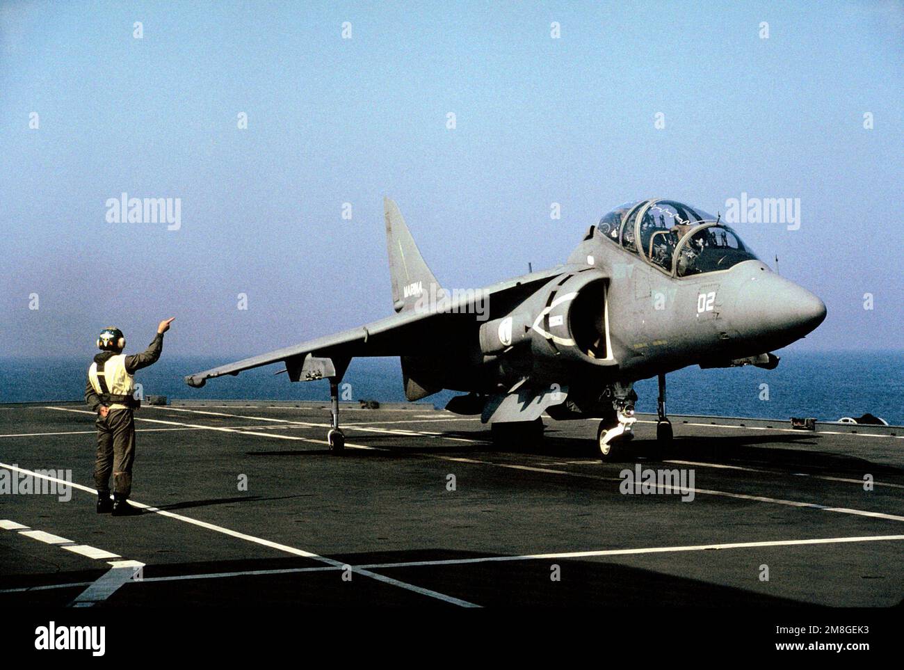 A flight deck crew member signals to the pilot of an Italian TAV-8B ...