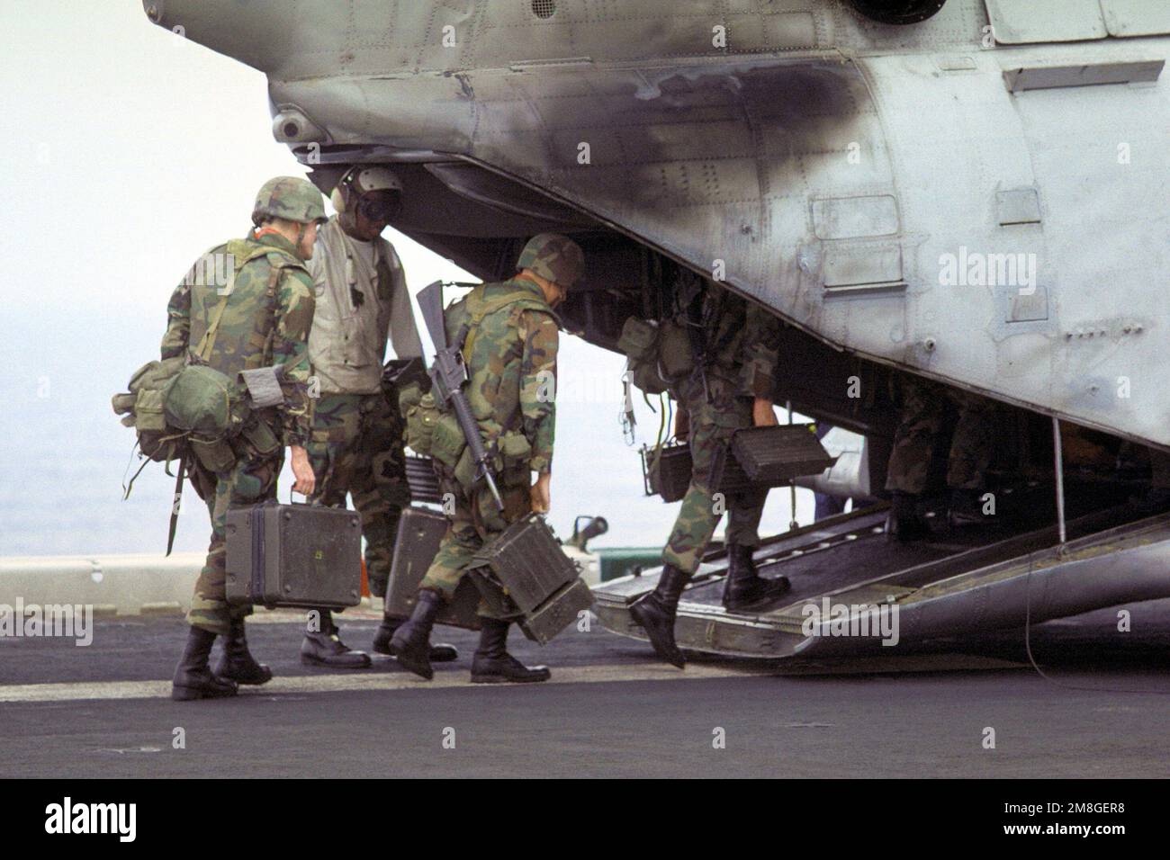 Marines board a CH-46 Sea Knight helicopter on the flight deck of the ...