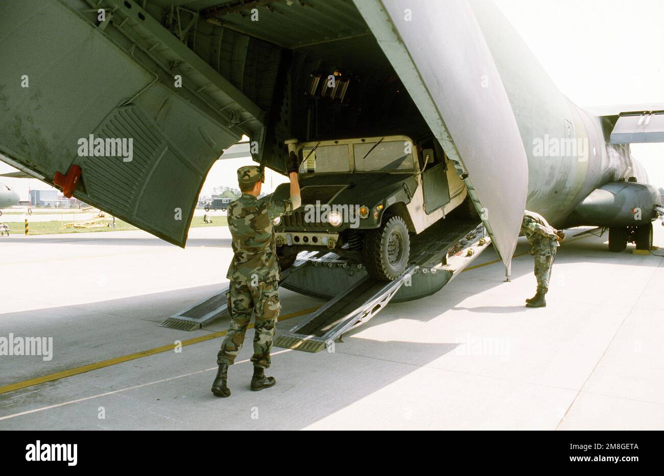 A member of an aerial port squadron directs the loading of an M-998 ...