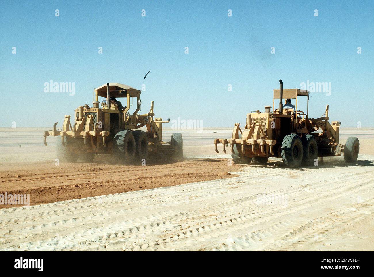 Civilian contractors smooth out the sand during preparation of an air ...