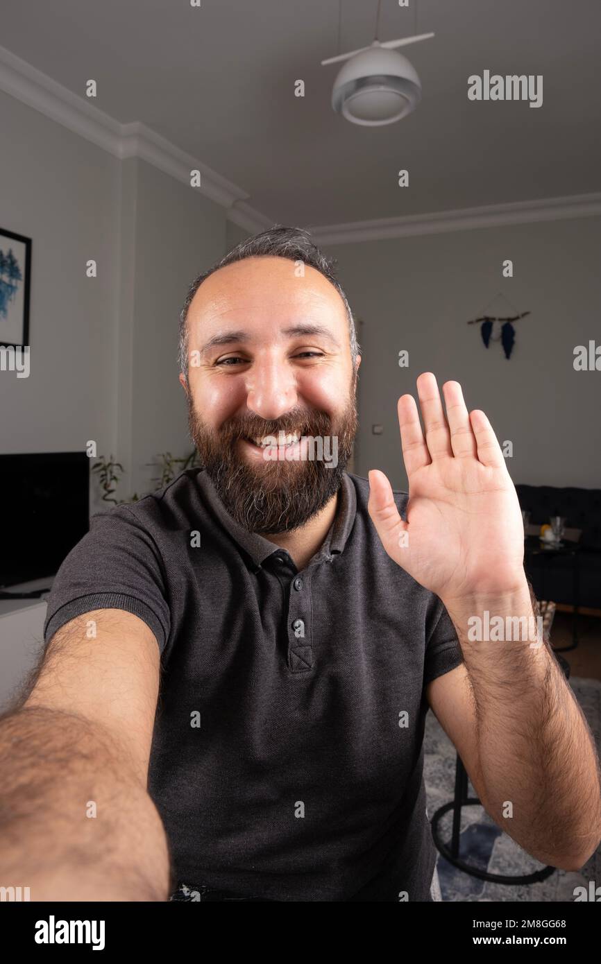 Handsome millennial man wave hand. Looking at web or smartphone camera ...