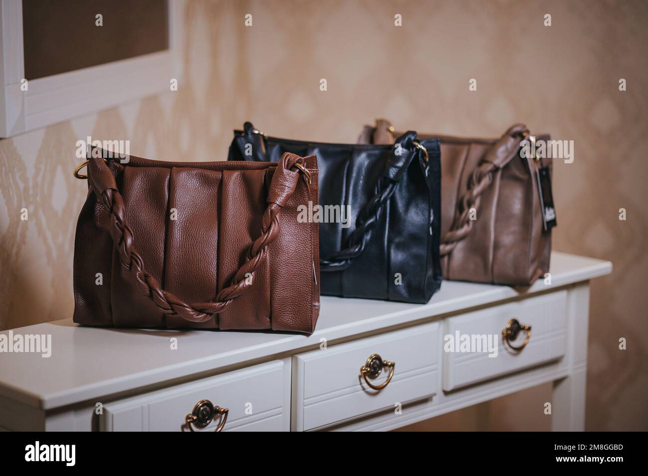 Three elegant leather bags on top of a white table Stock Photo - Alamy