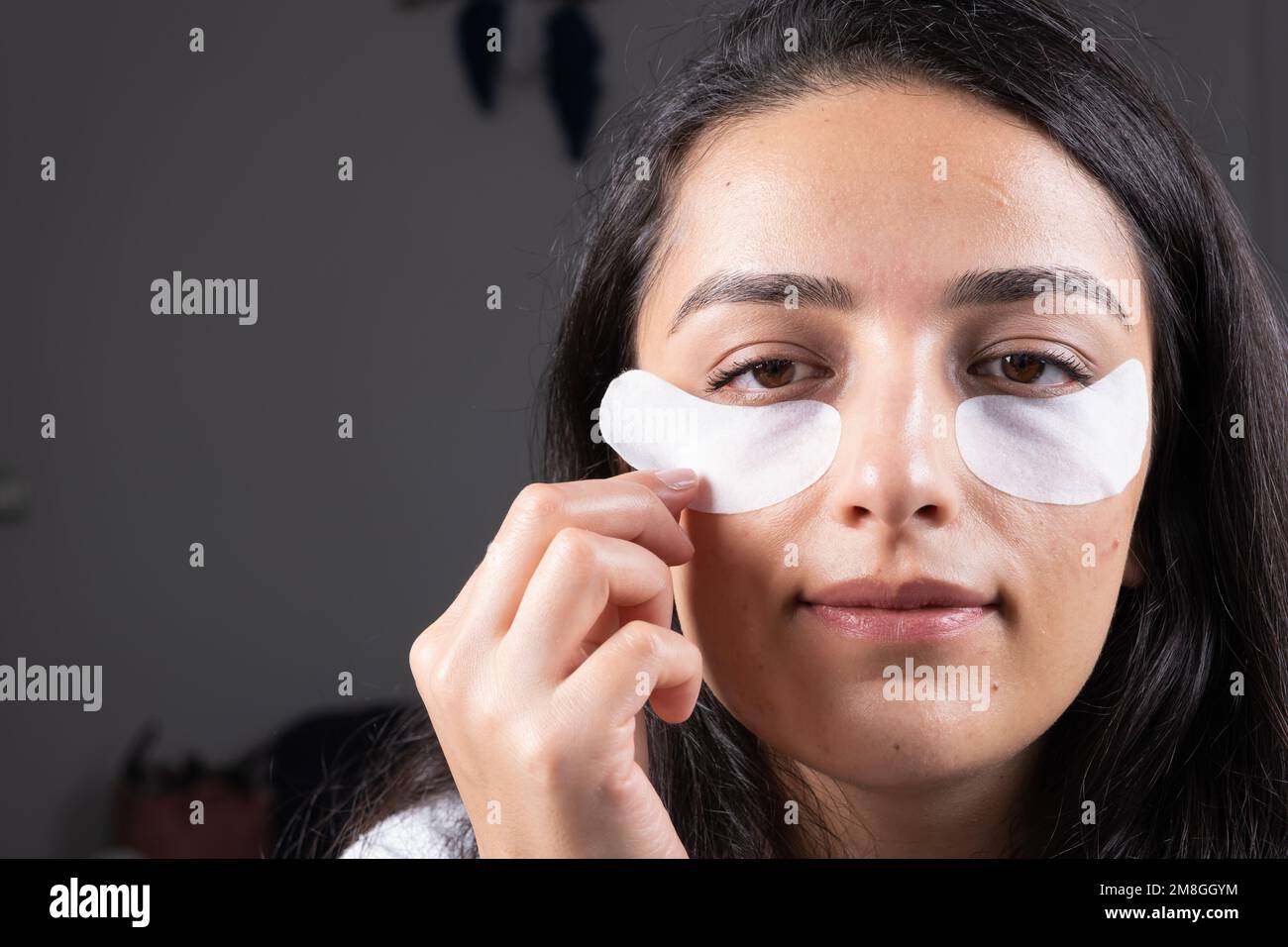 Healthy young lady looking camera with eye care patches on face. Pretty ...