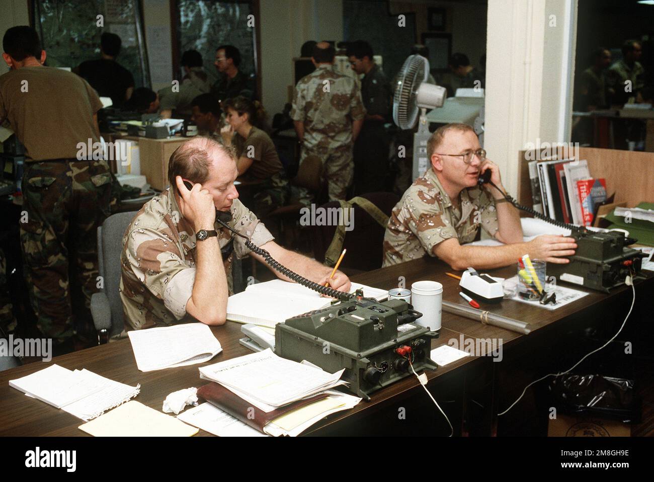 Two U.S. military officers conduct support activities using telephones ...