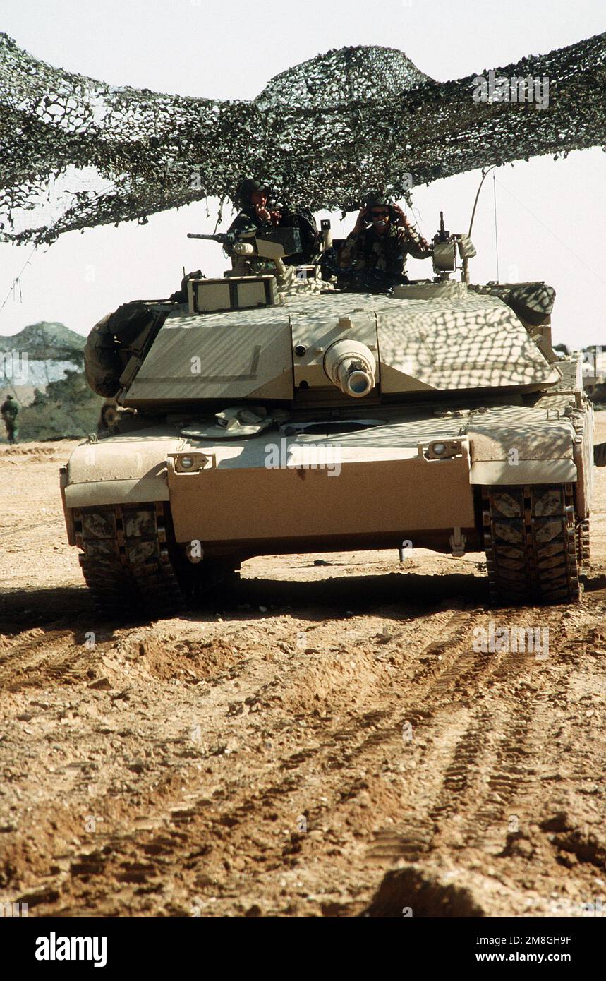 Army personnel man an M-1A1 Abrams main battle tank camouflaged with ...