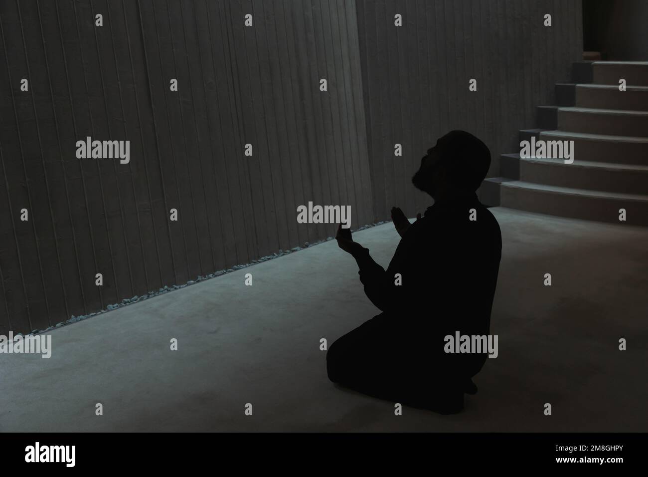 Muslim man praying in the mosque with raising hands. Silhouette of a ...