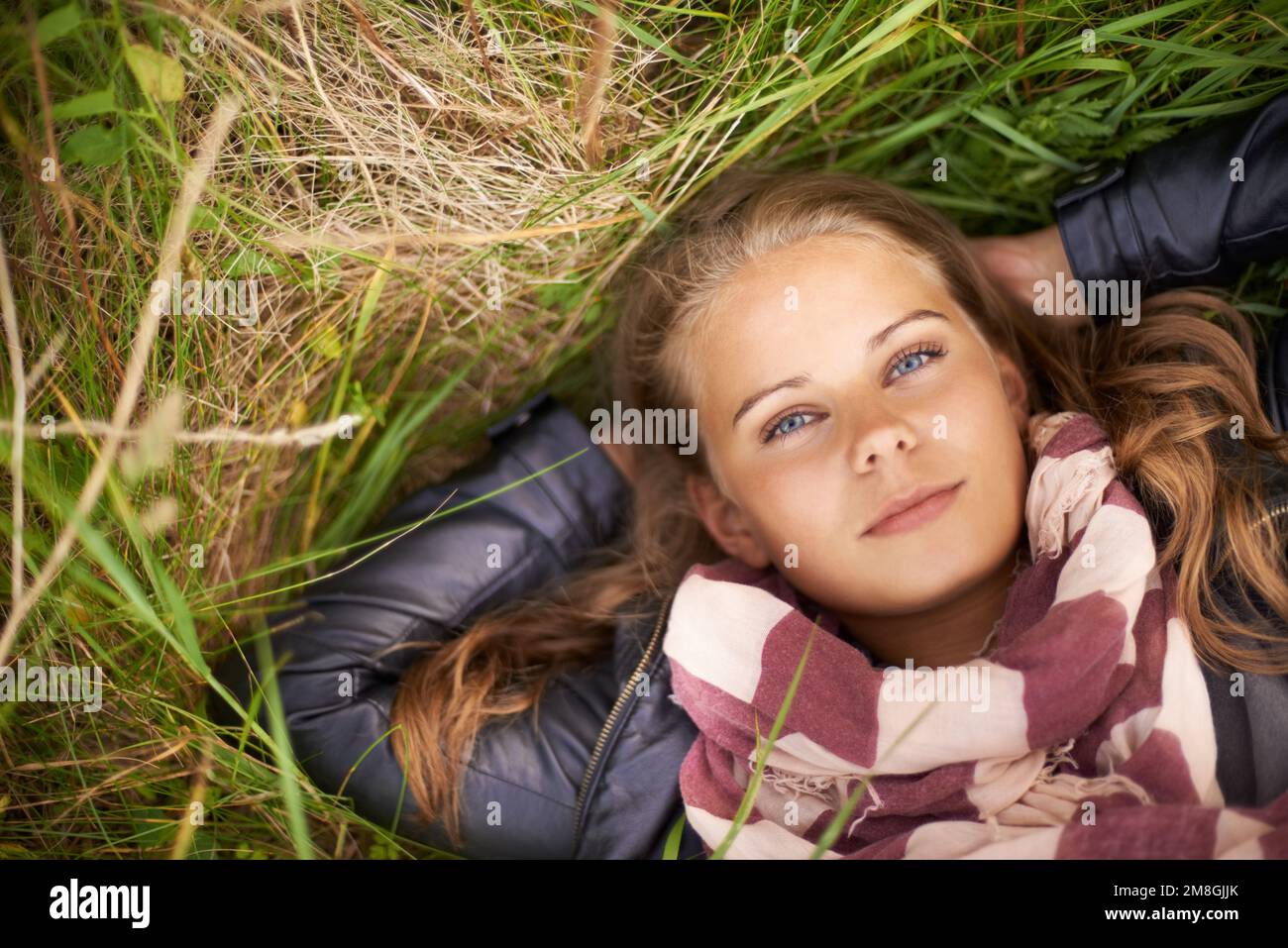 Surrounded by nature. Portrait of an attractive woman lying on her back ...