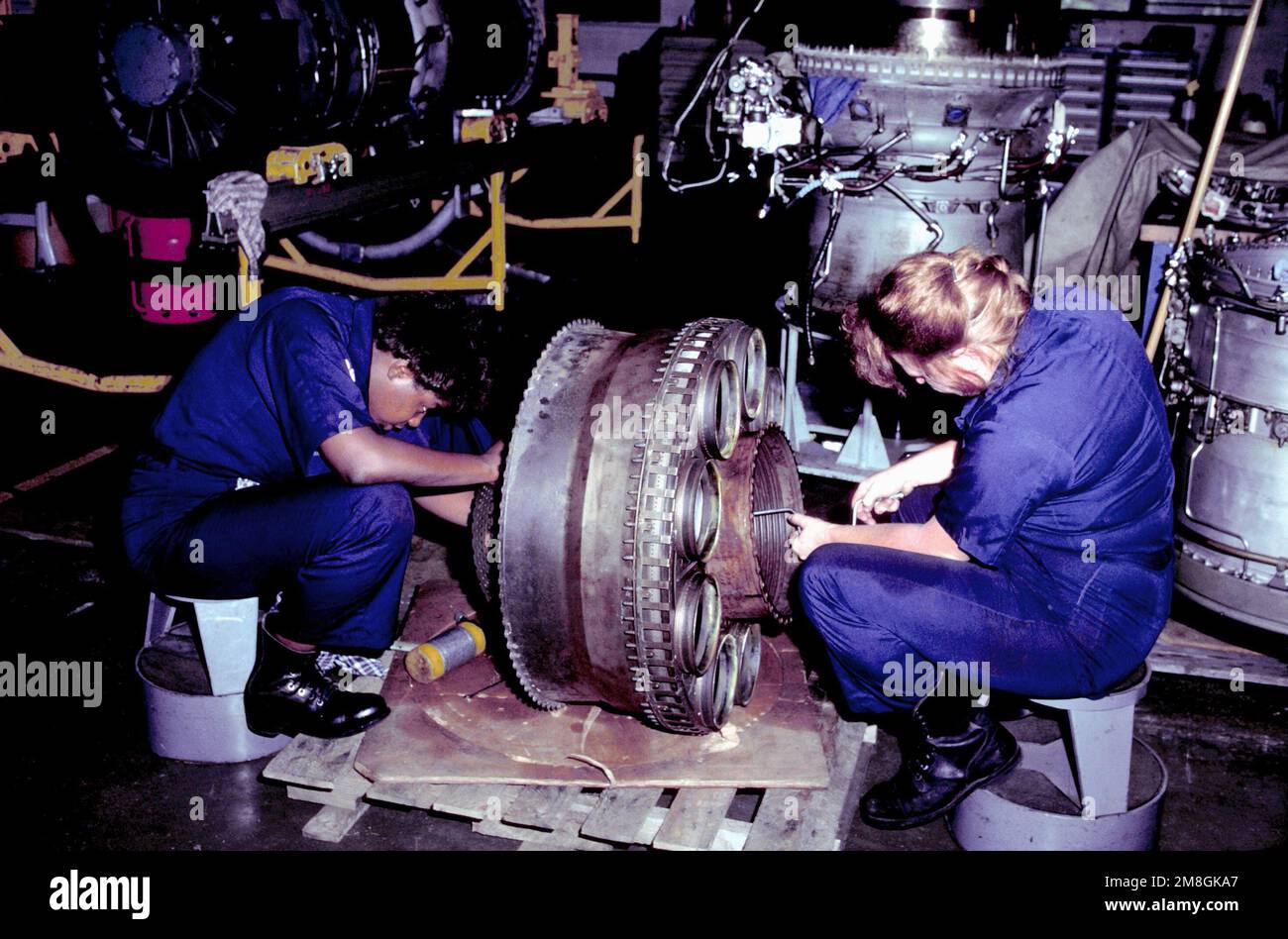 Two aviation machinist's mates service the compressor case of a jet ...