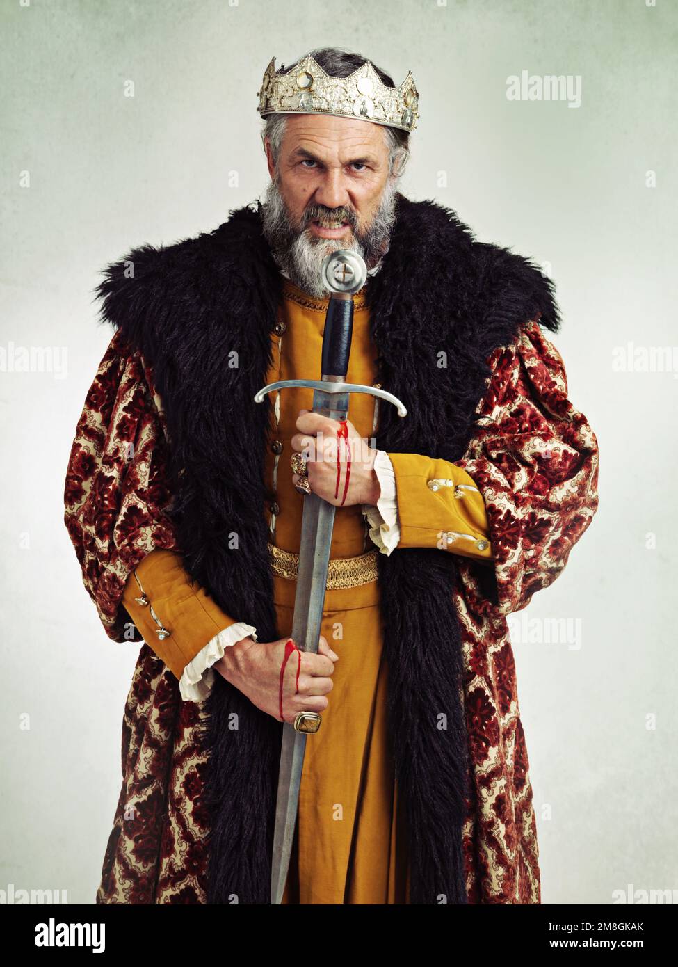 King, angry and portrait of man with sword in studio isolated on a gray ...