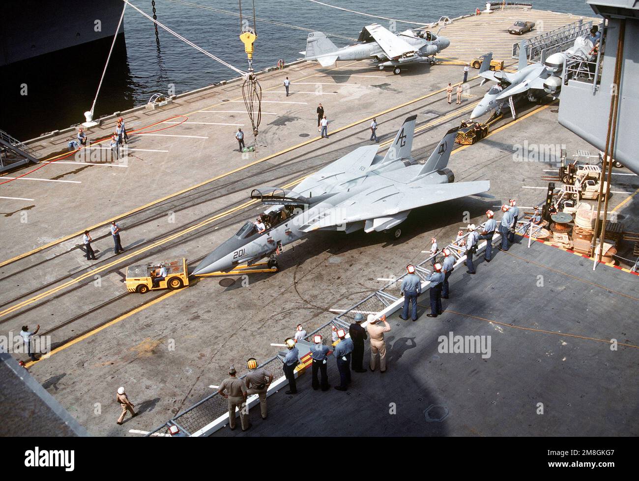 An MD-3A tow tractor positions a Fighter Squadron 142 (VF-142) F-14A ...