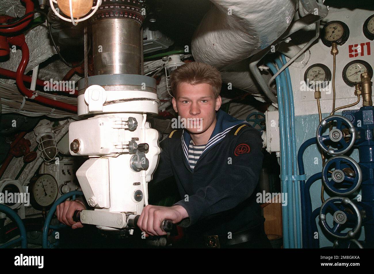 A Russian sailor poses for a photograph while manning a periscope ...