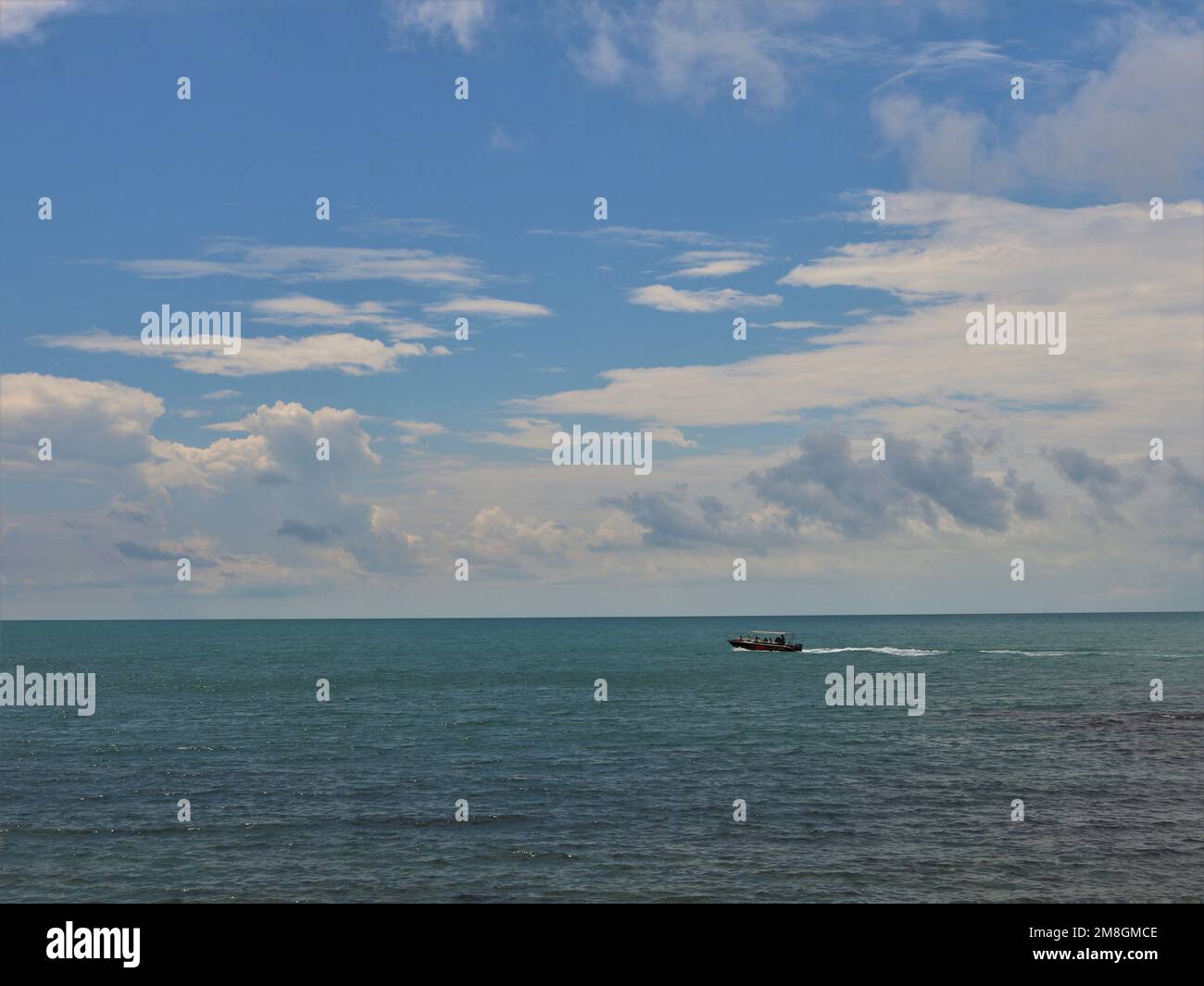 a small boat rushes along the expanse of sea water in the distance ...