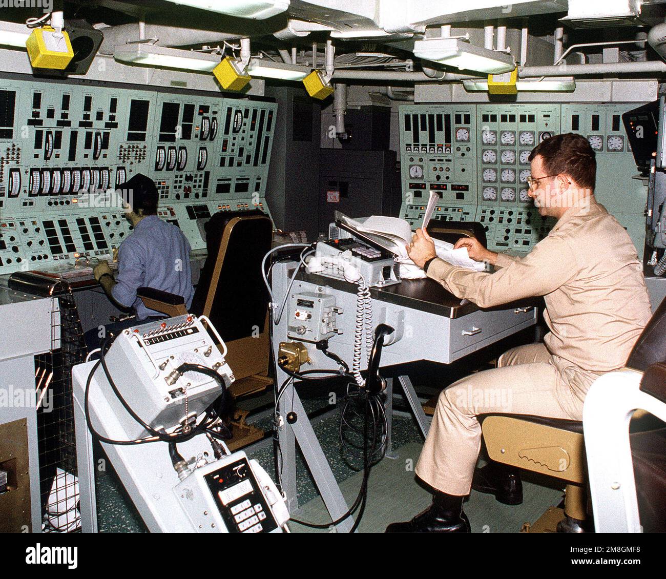 Crew members review operations procedures in the engine control room on ...