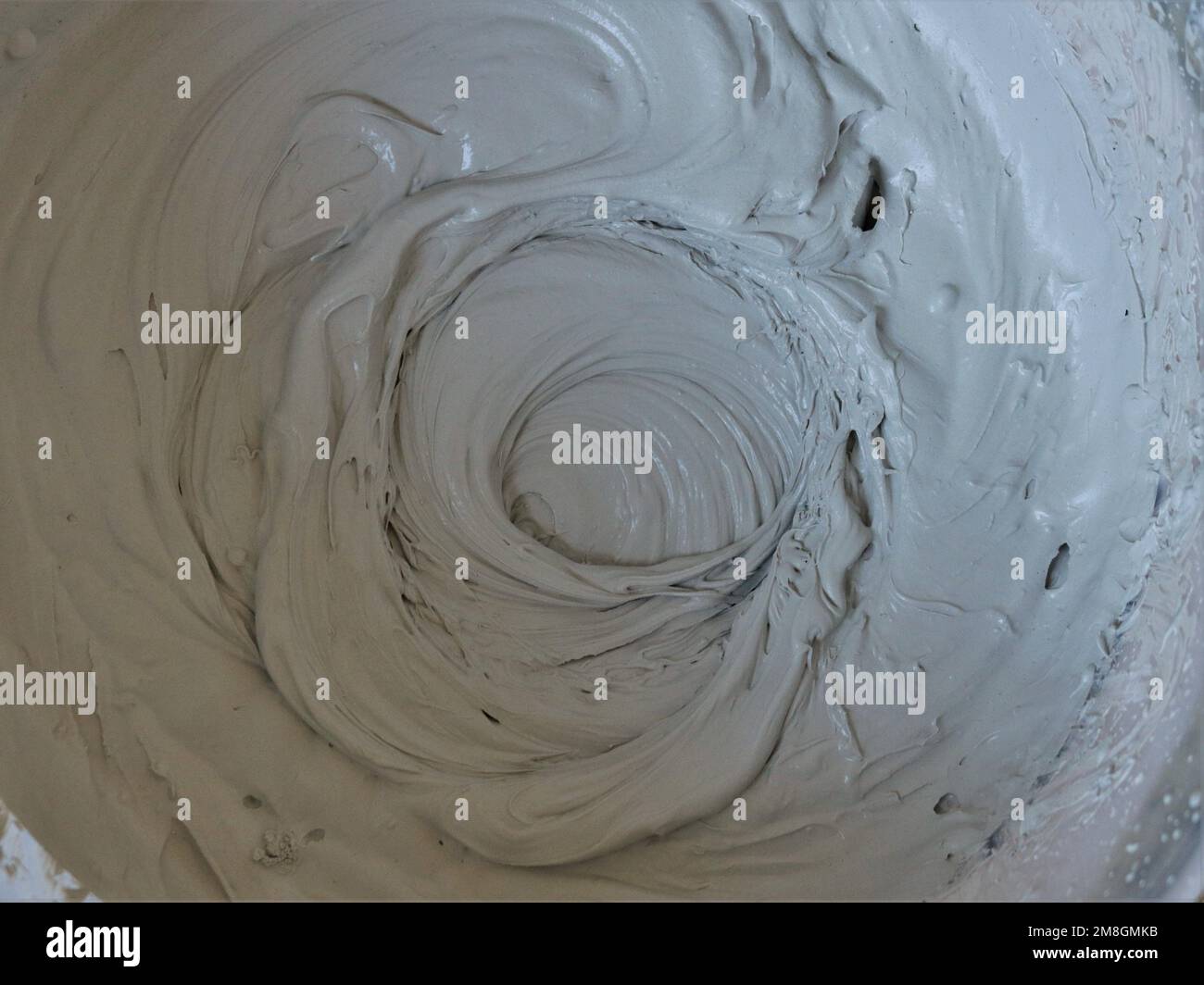 elastic gray mass of mortar swirling with smooth waves in a bucket top ...