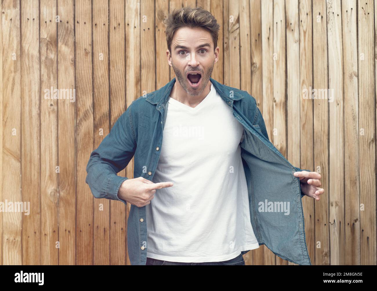 Young handsome man is standing on a light wooden wall background. Guy ...